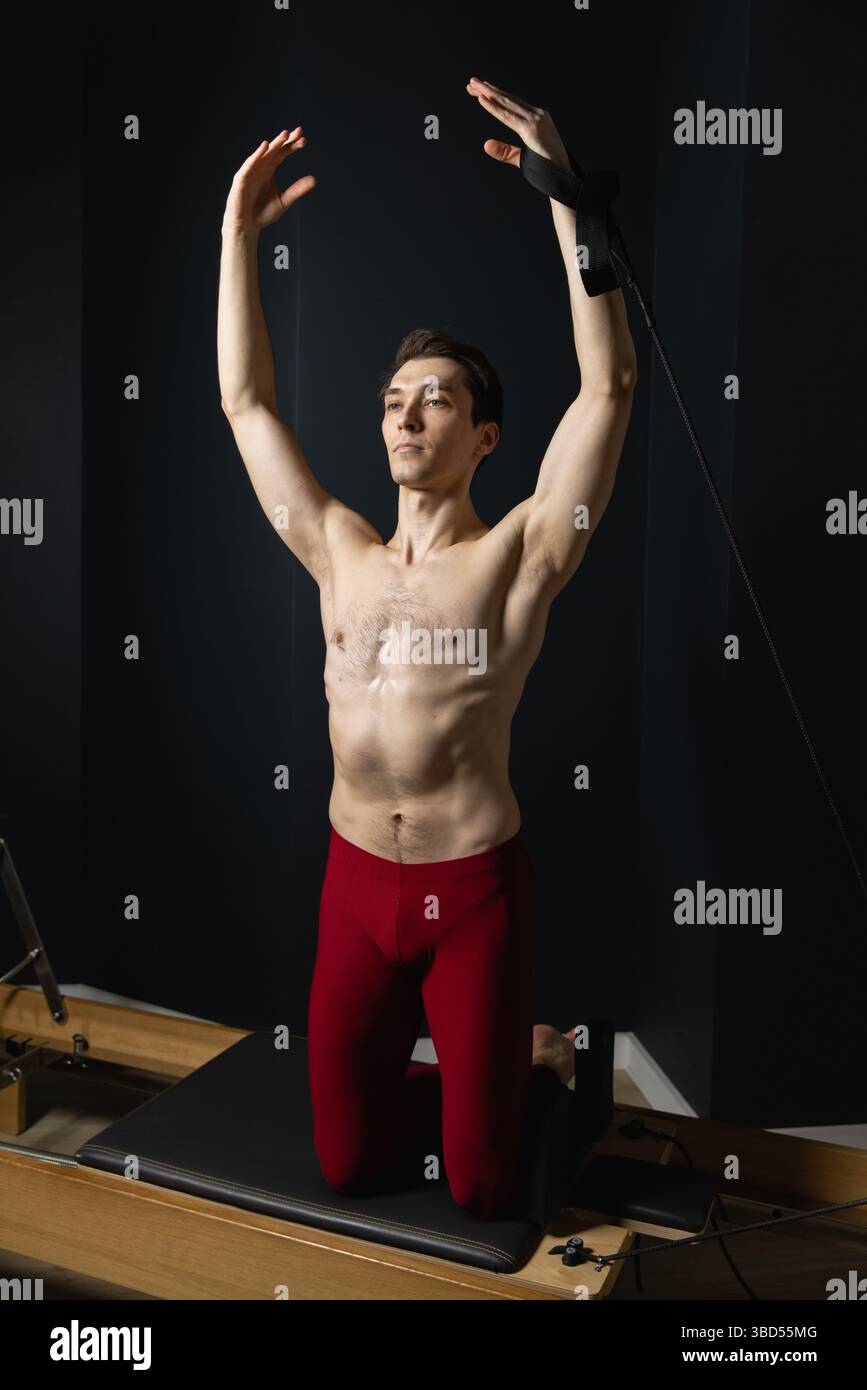 Slim male ballet dancer trains on Pilates equipment. Elegant pose, core ...