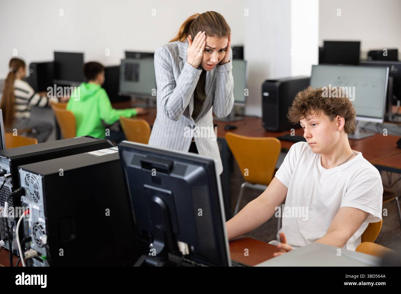 Frustrated teacher talking to neglectful teenage student in computer ...