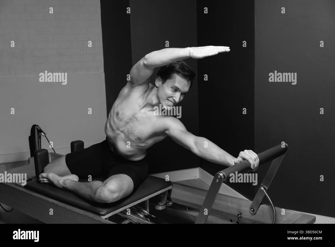 Slim male ballet dancer trains on Pilates equipment. Elegant pose, core ...