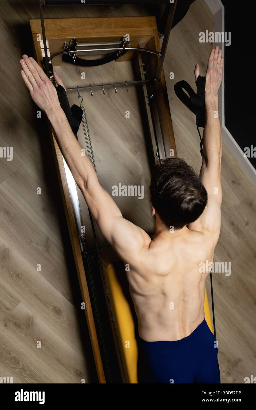 Slim male ballet dancer trains on Pilates equipment. Elegant pose, core ...
