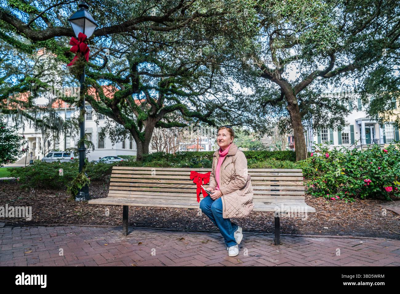 A beautiful mature woman sitting on a bench in a city park in Savannah ...
