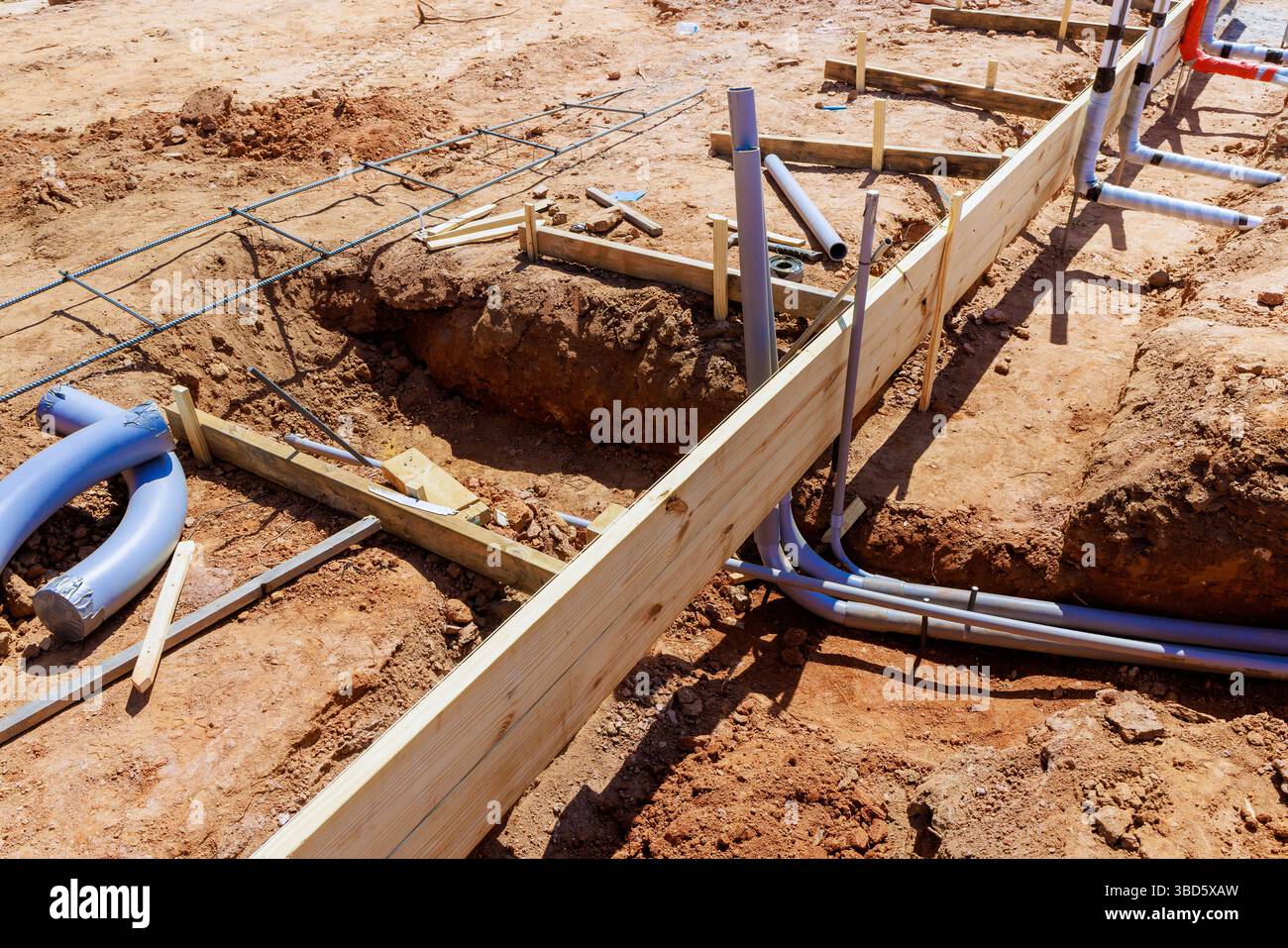 Workers set up plumbing foundation forms on construction site during ...