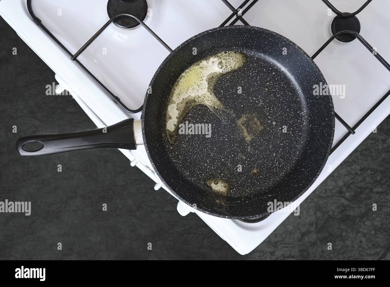 A frying pan on a gas stove, with melted butter pooling in the bottom ...