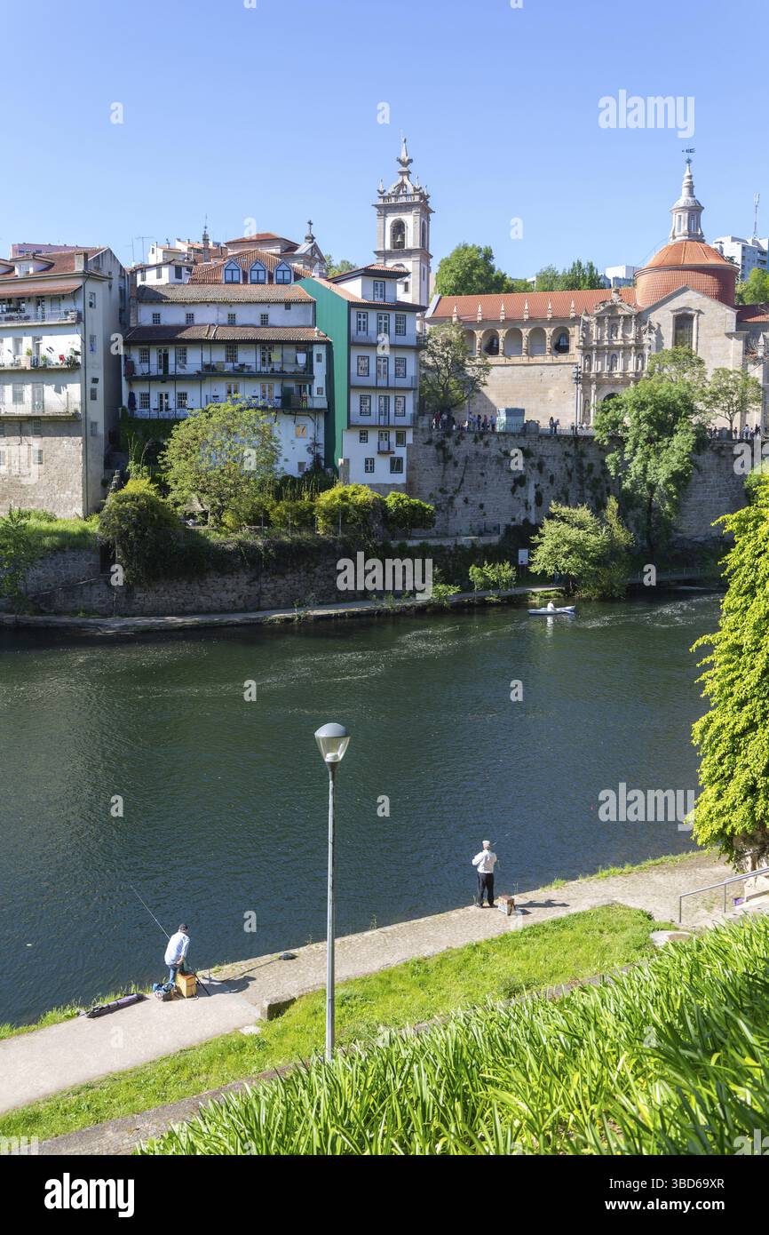 People fishing on riverbank of River Tamega, historic buildings of ...
