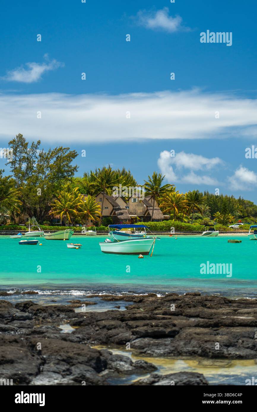 A group of small boats anchored near a beachfront lined with thatched ...