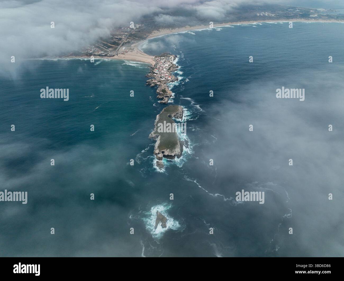 Aerial view of Baleal town and cliffs under cloudy skies across open ...