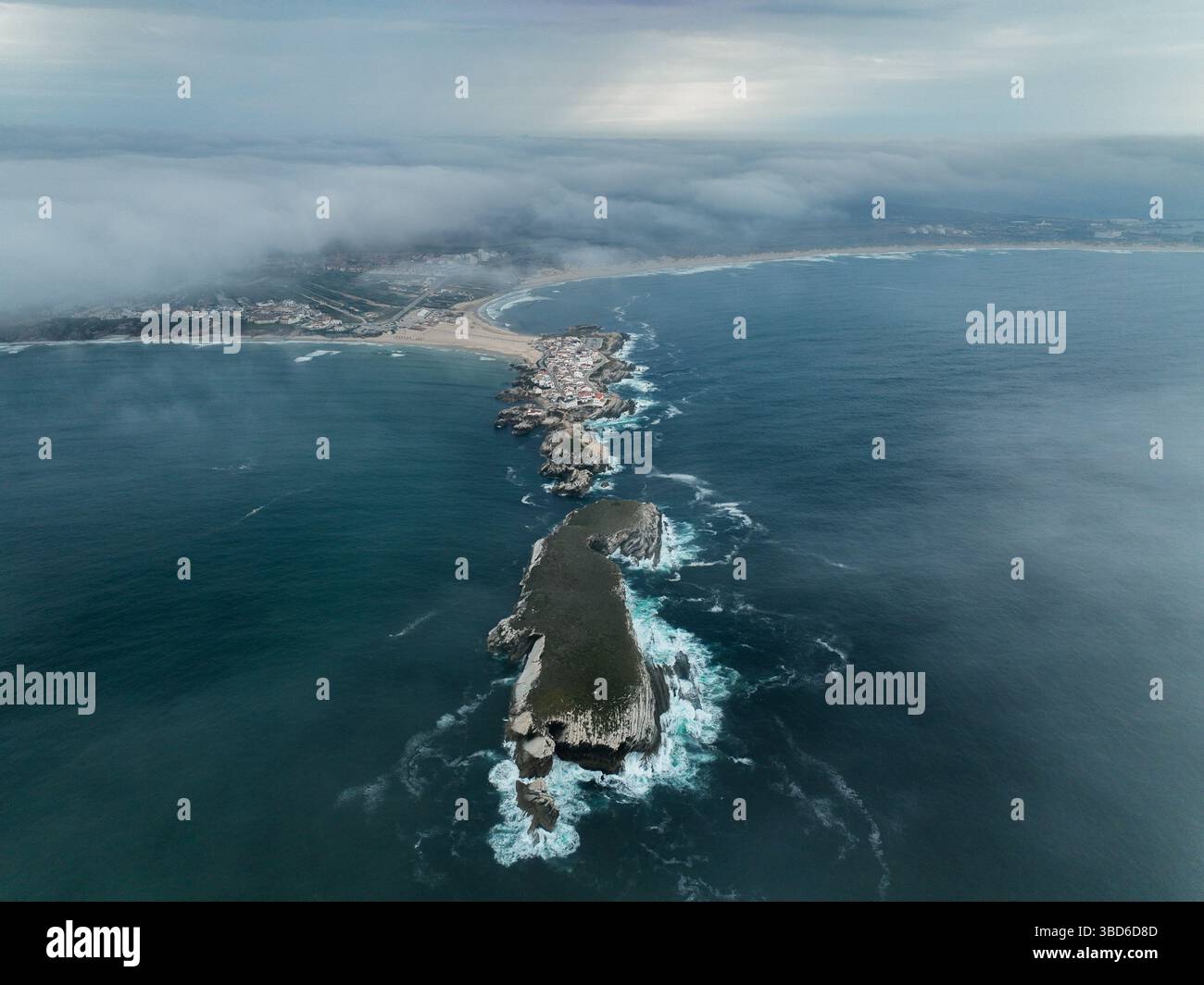 Aerial view of Baleal town and cliffs under cloudy skies across open ...