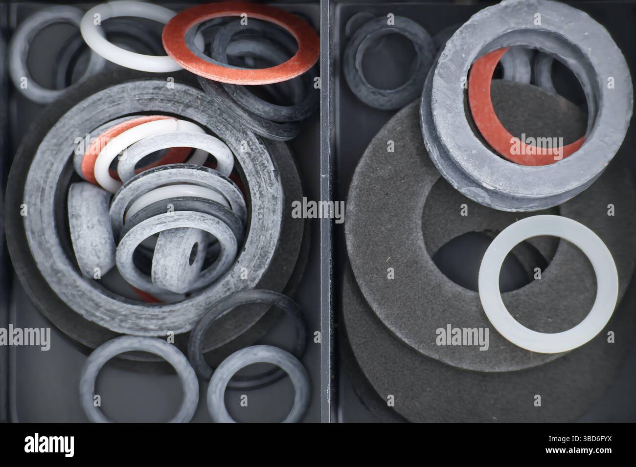 Various sizes and colors of rubber washers, neatly arranged within a ...