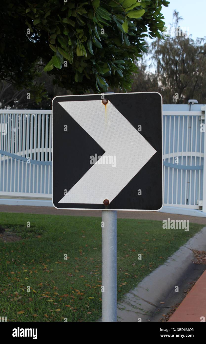 Road sign with a white chevron arrow pointing to the right mounted on a ...