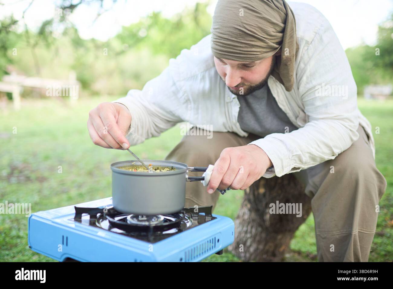 Male traveler cooks a veggie lunch outdoors, rice with vegetables ...