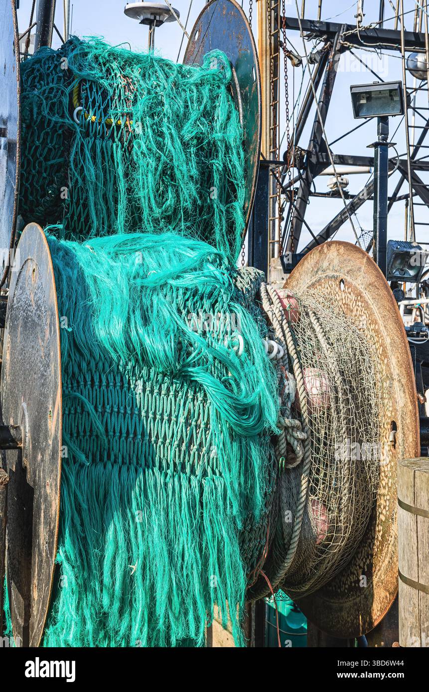 Detail of rolled-up green industrial fishing nets on spindle aboard a ...