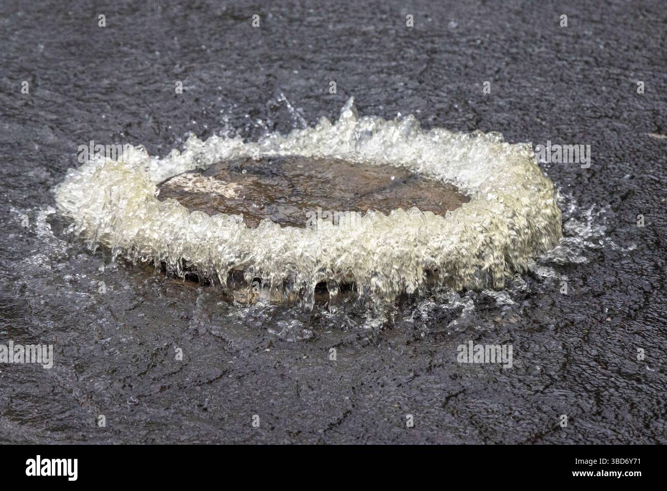 Storm water bubbling from drain inspection plate Stock Photo - Alamy
