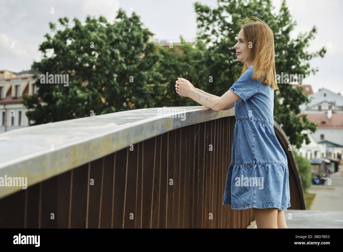 Woman leaning on a railing and surveys neighbourhood from height of ...