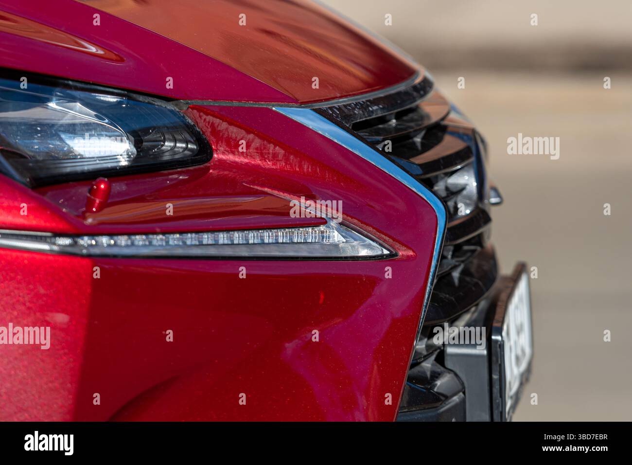 Shiny red car showcases its sleek front grille and detailed headlights ...