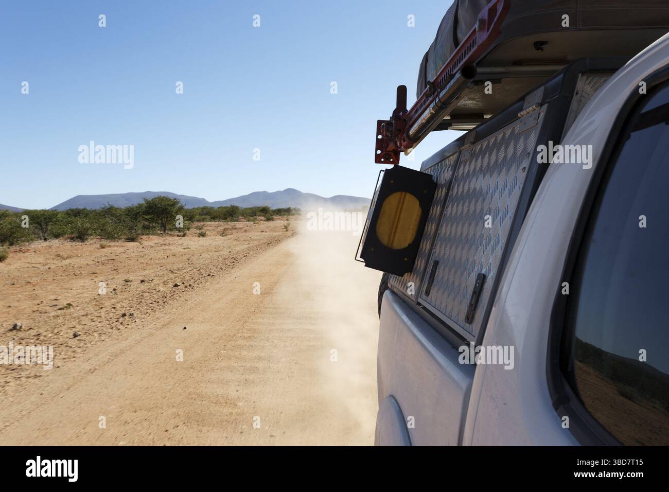 Looking back while driving a 4x4 on a gravel road with a dust cloud ...