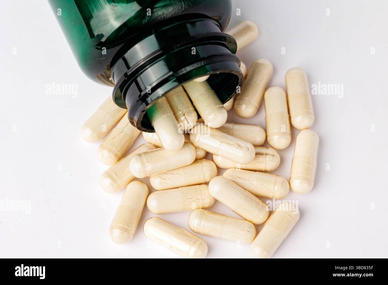 Spilled capsules from green bottle on white background Stock Photo - Alamy