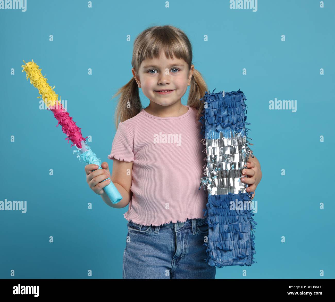 Happy girl with bright pinata and stick on light blue background Stock ...