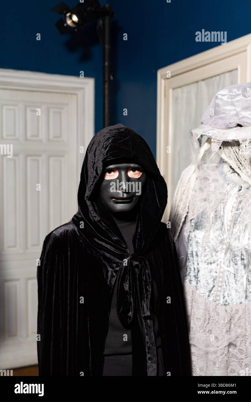 Mysterious figure dressed in black velvet cloak and dark mask, standing ...