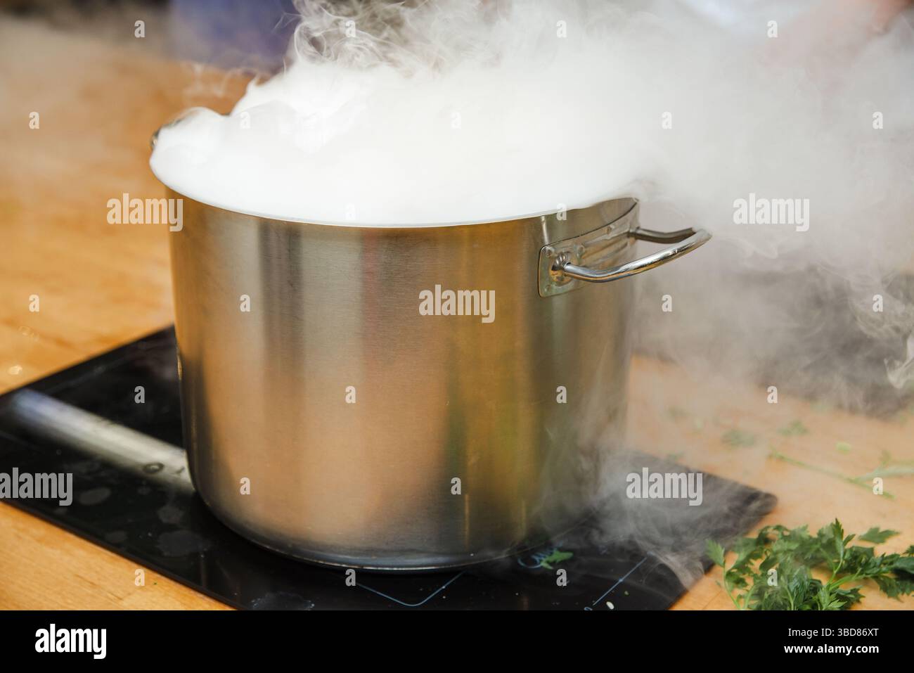 Large stainless steel pot on stove emitting heavy steam, overflowing ...
