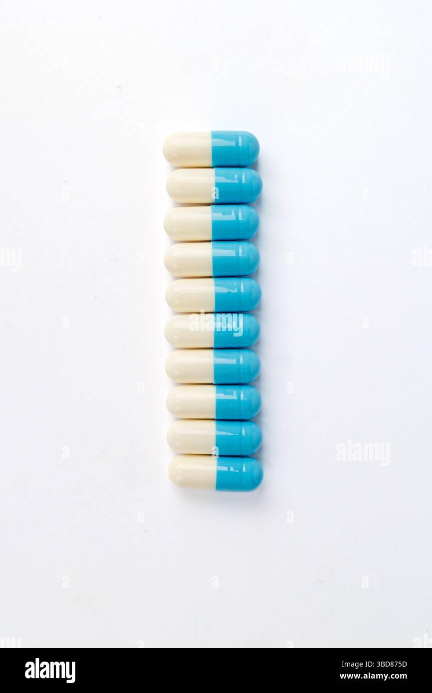 Blue and white medical capsules lined vertically Stock Photo - Alamy