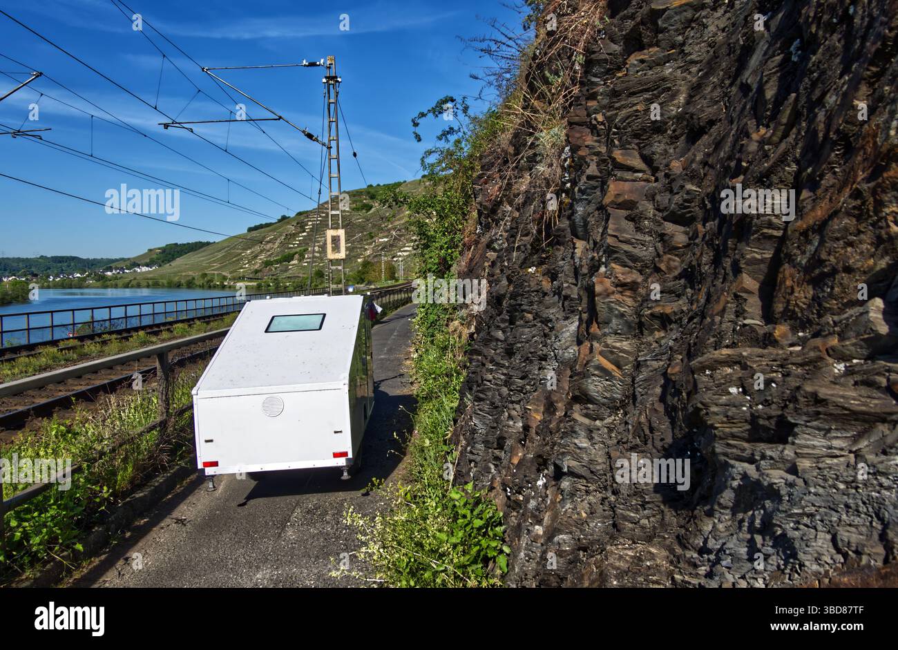 Towing a compact, white camper trailer along a narrow bike path between ...