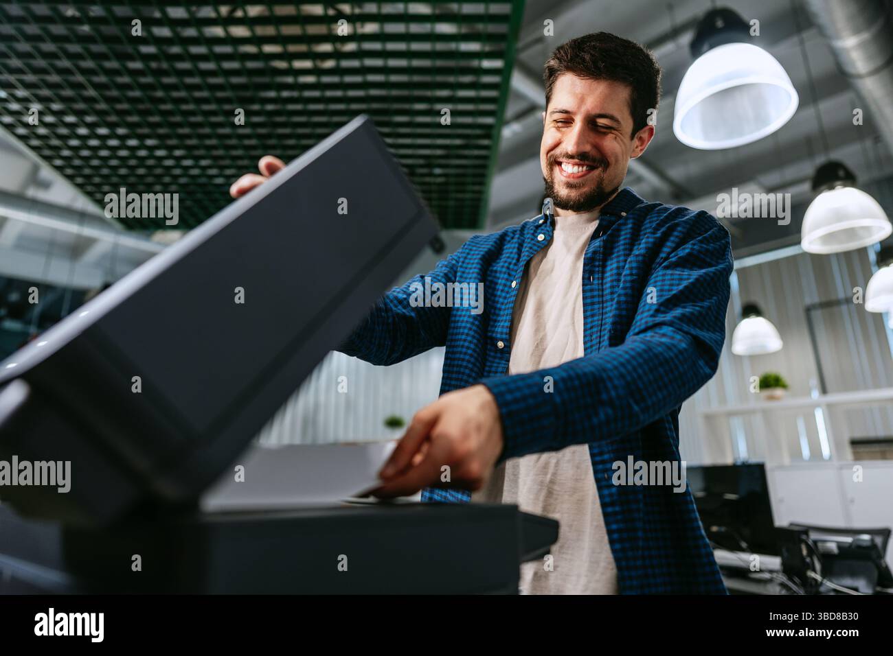 Man operating printer in modern office environment during working hours ...