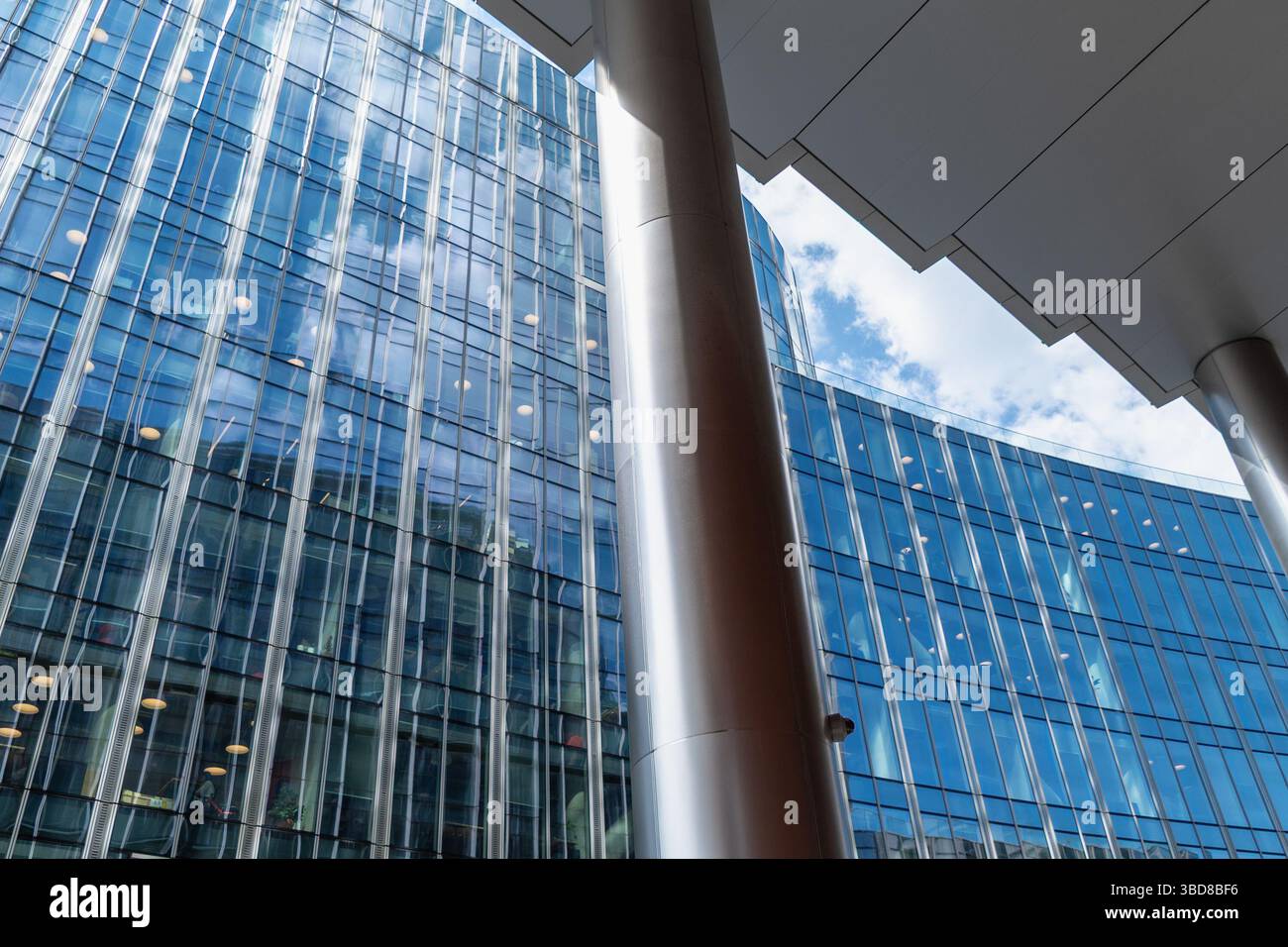 Modern glass office building with reflective windows and metal columns ...