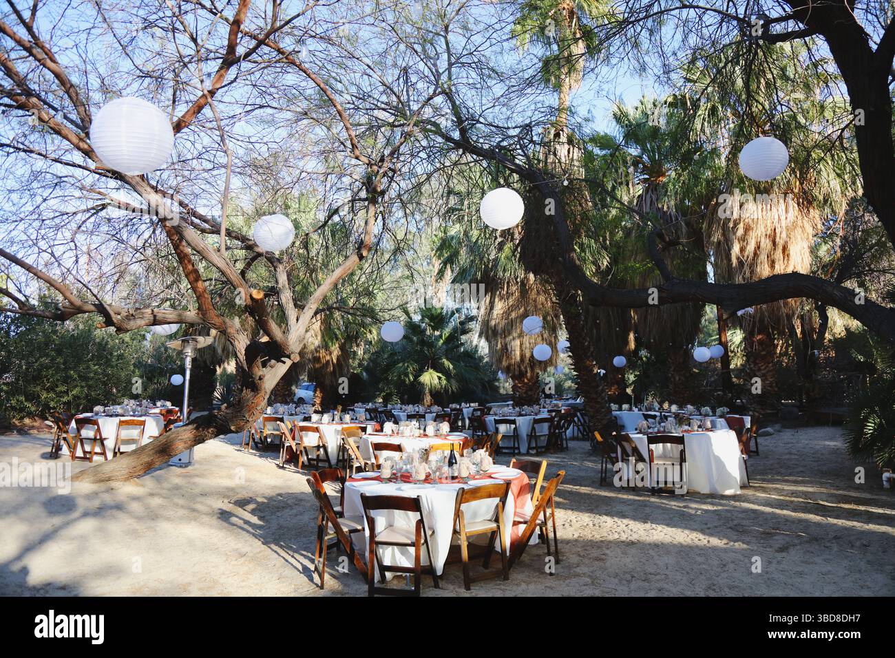 Rustic outdoor event with round tables and hanging lanterns Stock Photo ...