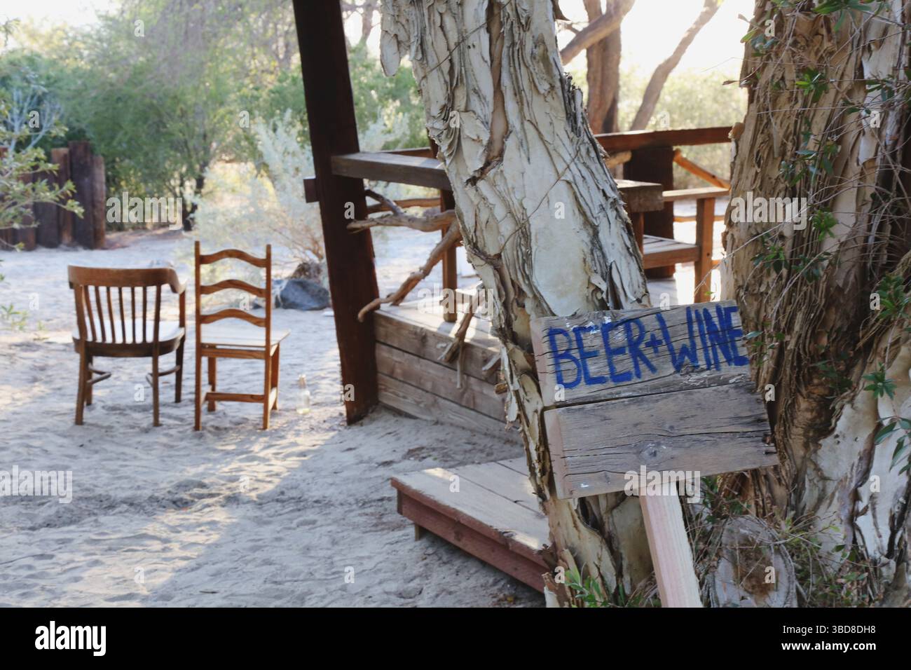 Rustic outdoor bar area with wooden chairs and a beer and wine sign ...