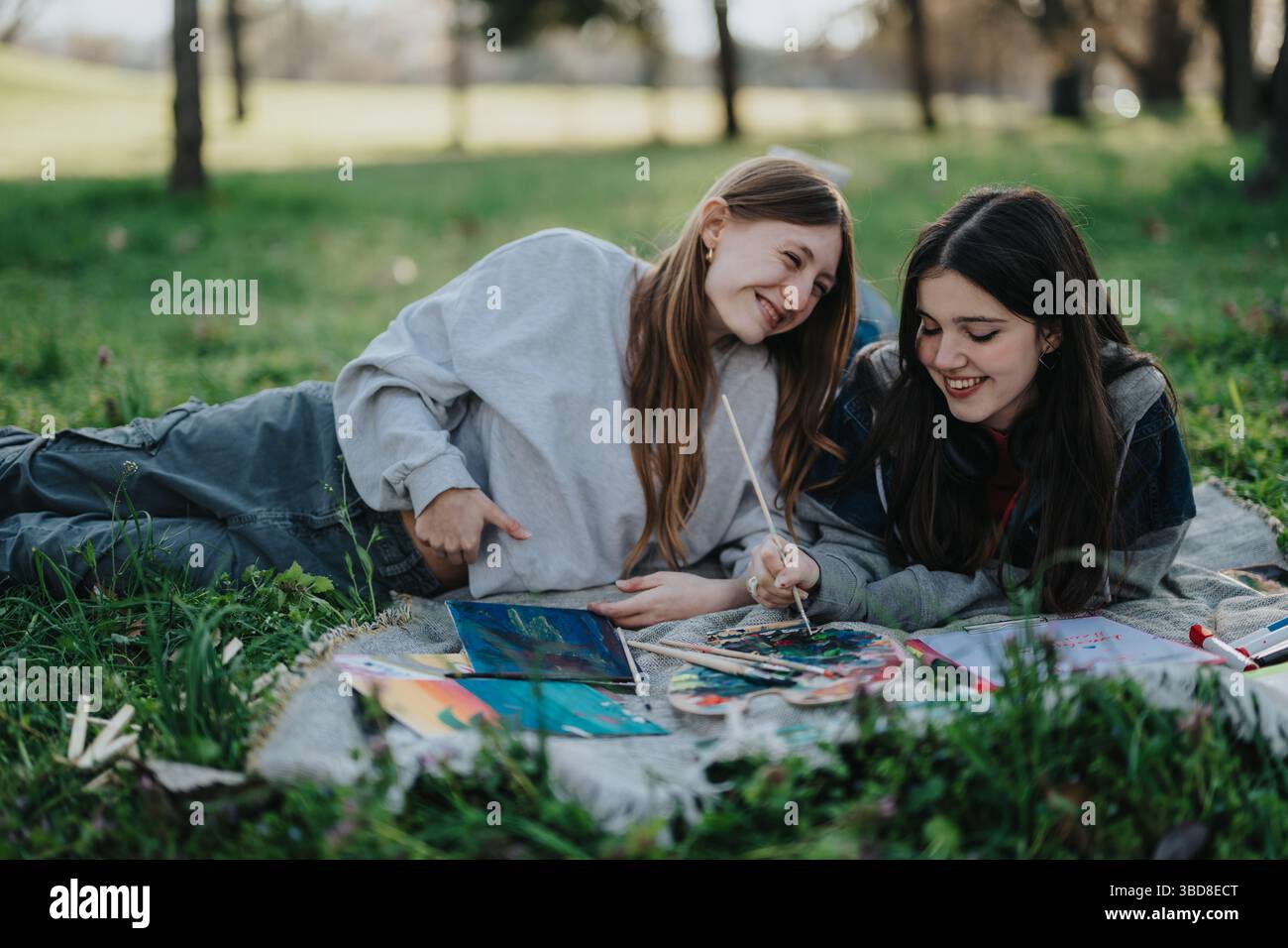 Two female friends creating artwork together in an outdoor setting ...