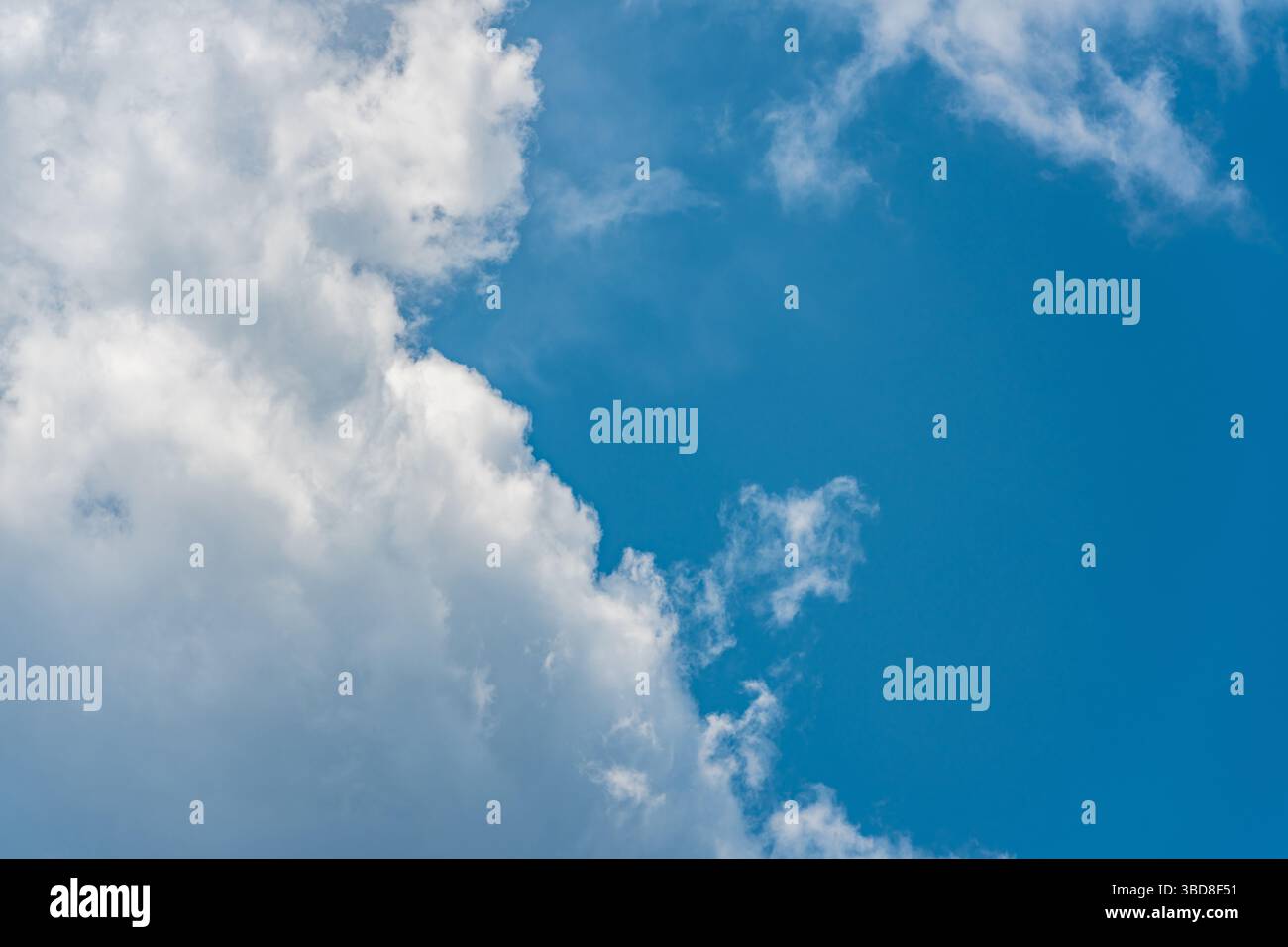 Fluffy white clouds in a bright blue daytime sky Stock Photo - Alamy