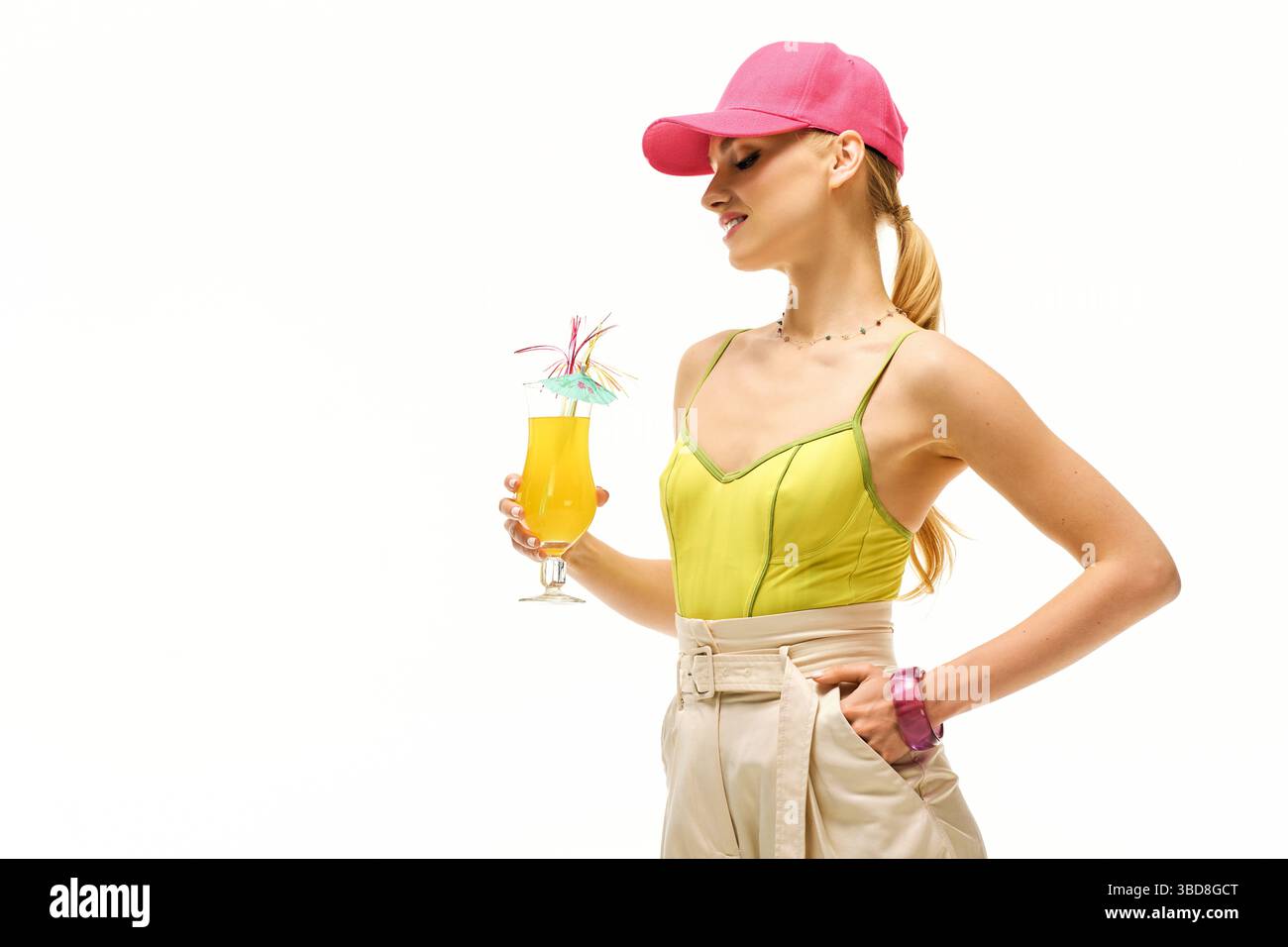 Brightly dressed woman enjoys a colorful tropical drink with a playful ...