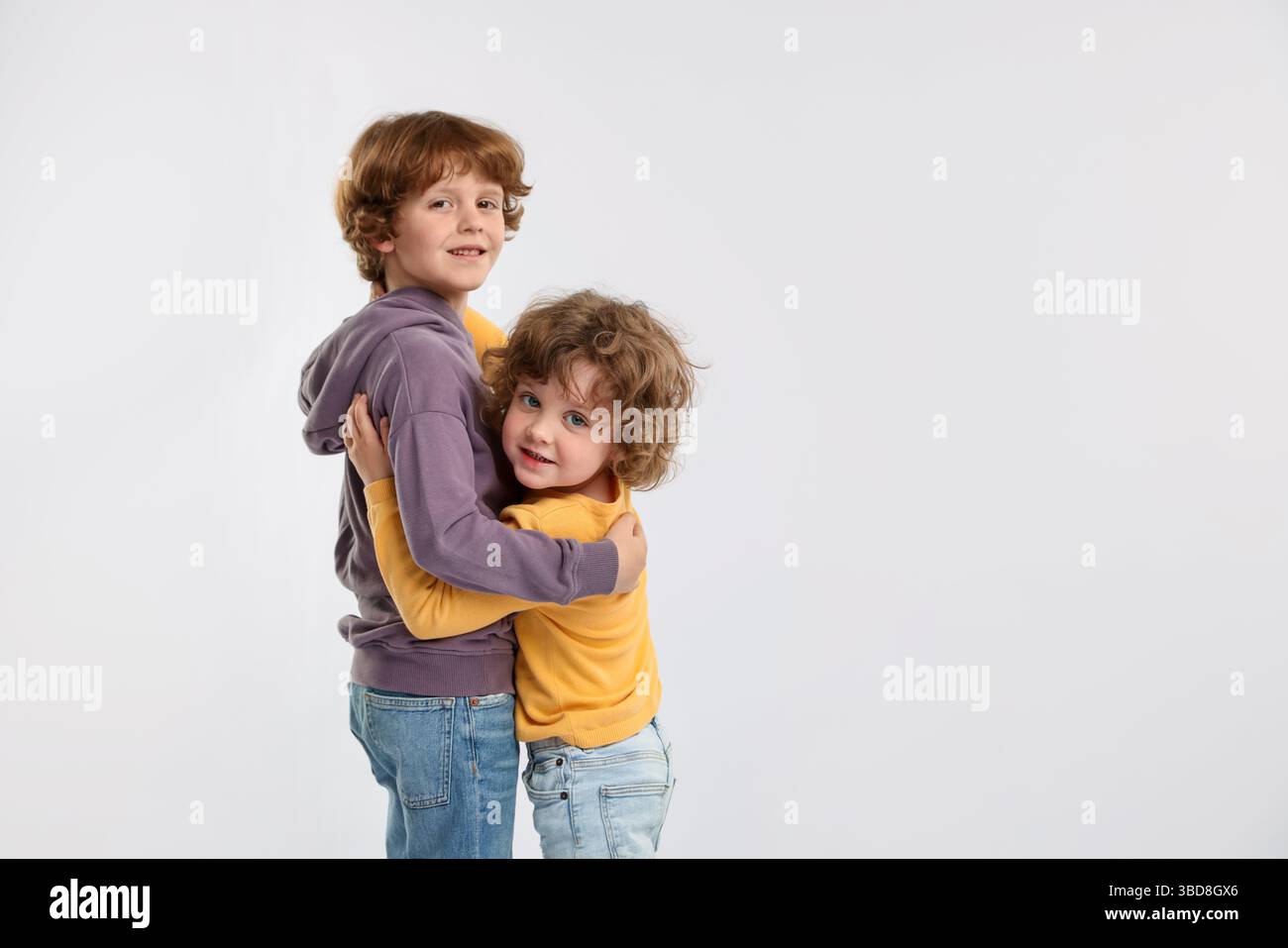 Cute little brothers hugging on white background Stock Photo - Alamy