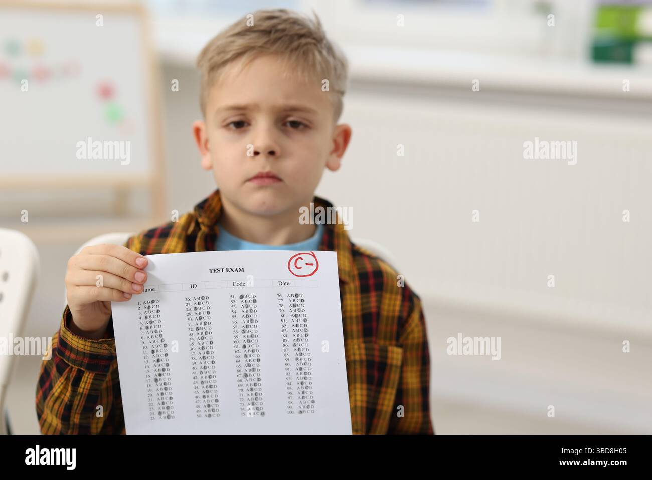 School grade. Sad boy holding answer sheet with letter C and minus ...