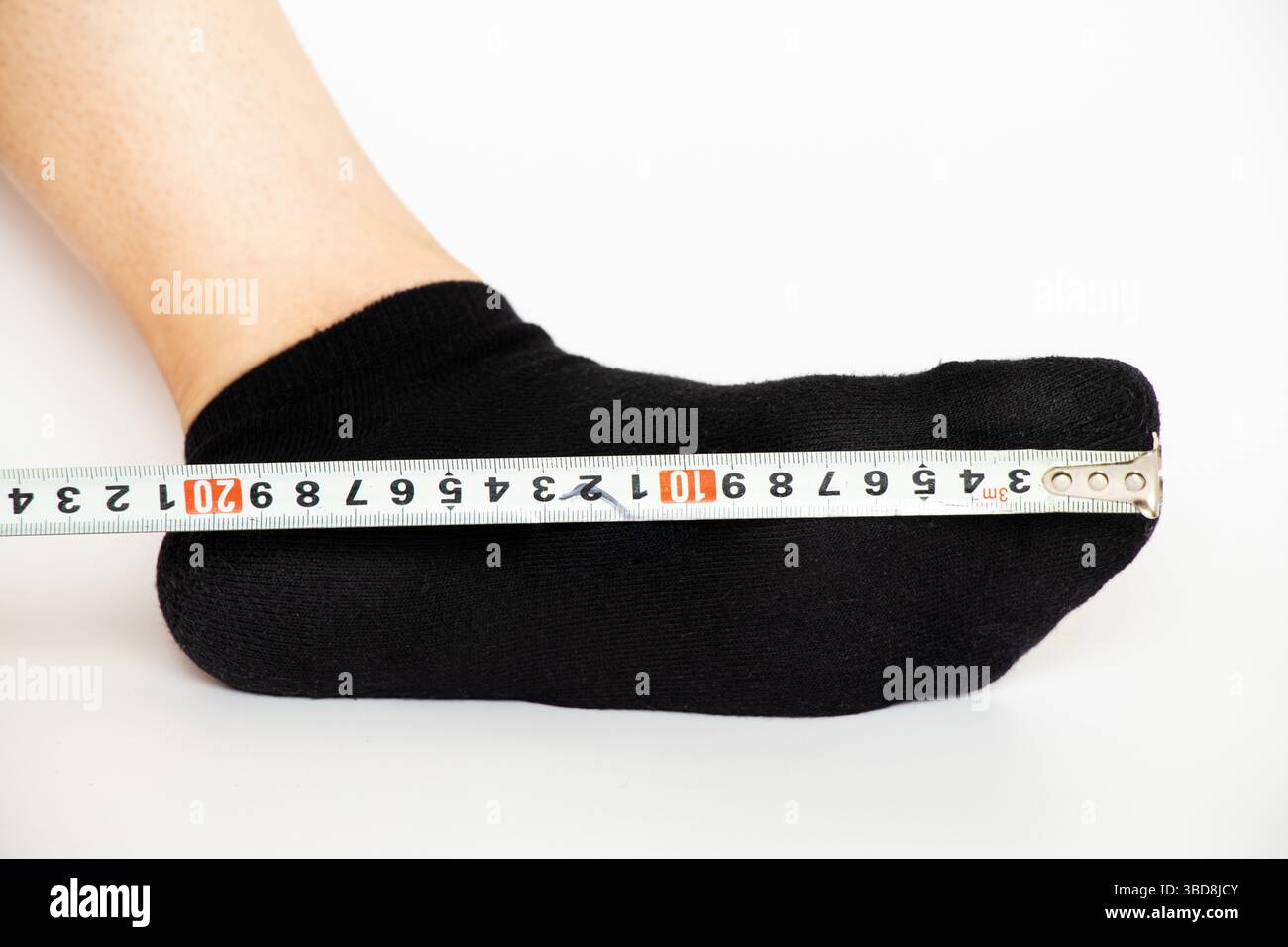 Female foot in sock and measuring tape on white background, measuring ...