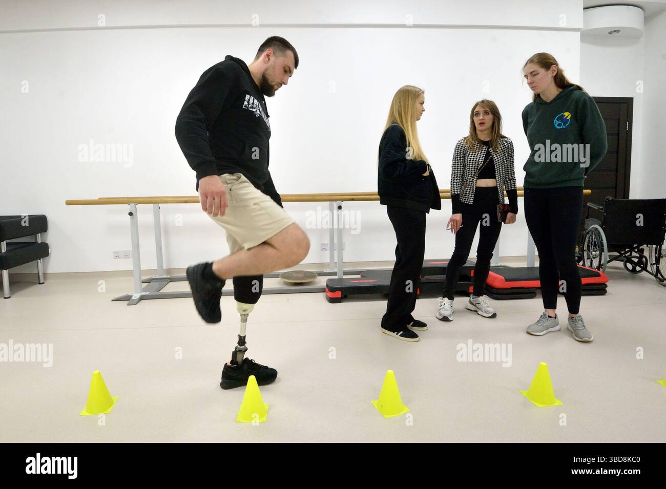 A patient with a prosthetic leg steps over cones during a training ...
