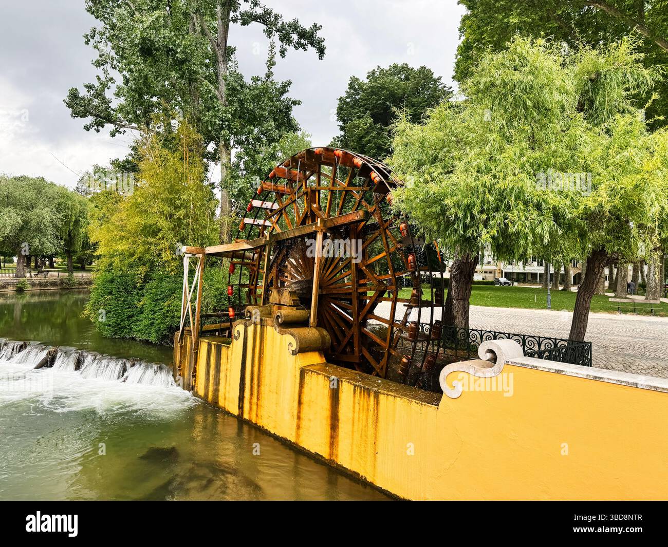 Rustic water wheel surrounded by greenery in a serene park in Tomar ...
