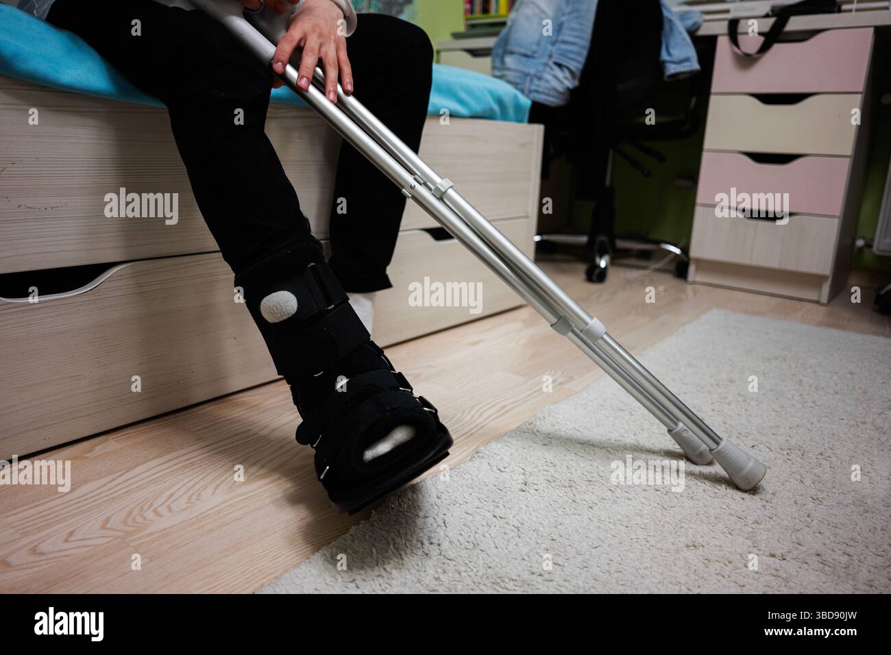 Injured individual with a leg brace and crutches sitting in a home ...