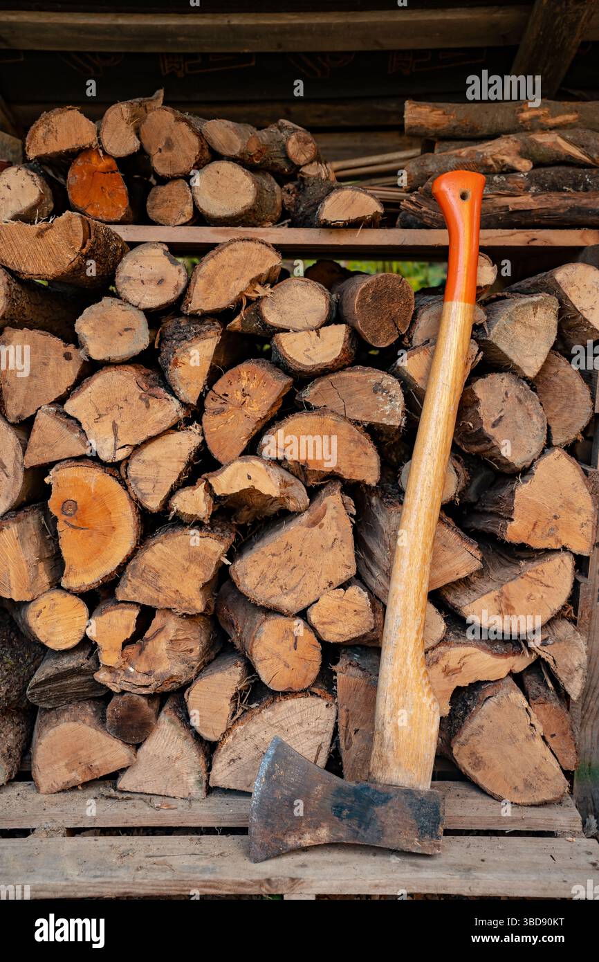 Axe in front of a stack of wood in a woodshed. Natural vertical ...