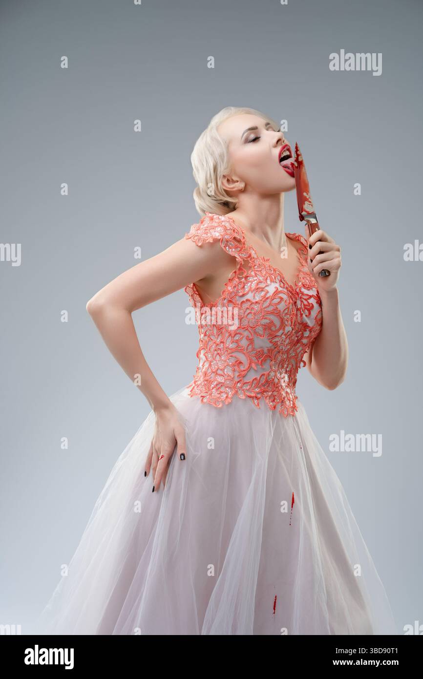 Bride with a bloody knife striking a dramatic pose in studio setting ...
