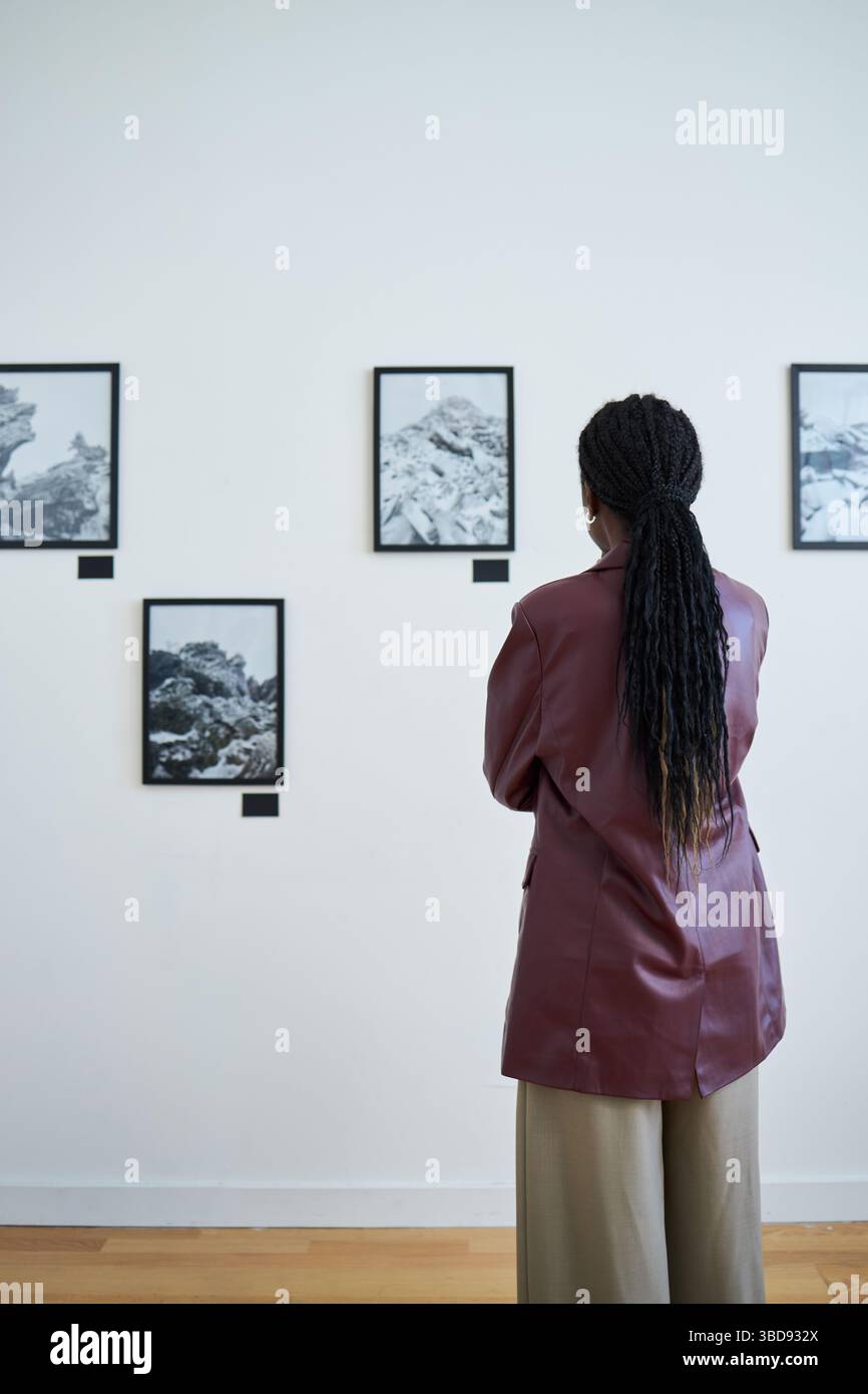 Woman observing black and white photographs on display in modern art ...