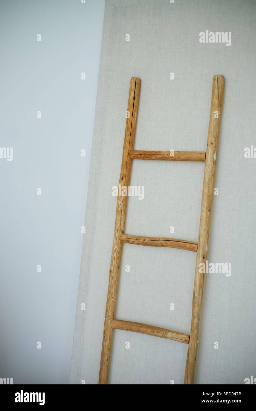 Simple wooden ladder with worn texture leaning against plain wall ...