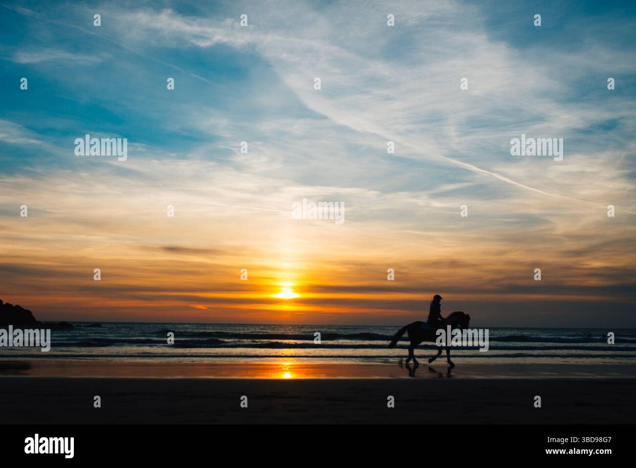 Silhouette of a horse and rider on Perranporth beach, Cornwall, at ...
