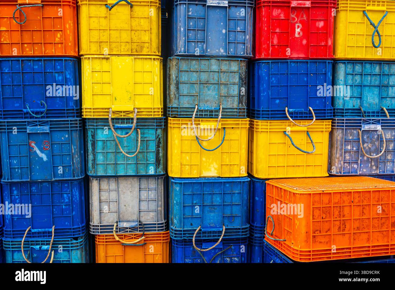 Stack of blue and yellow crates. The crates are stacked on top of each ...