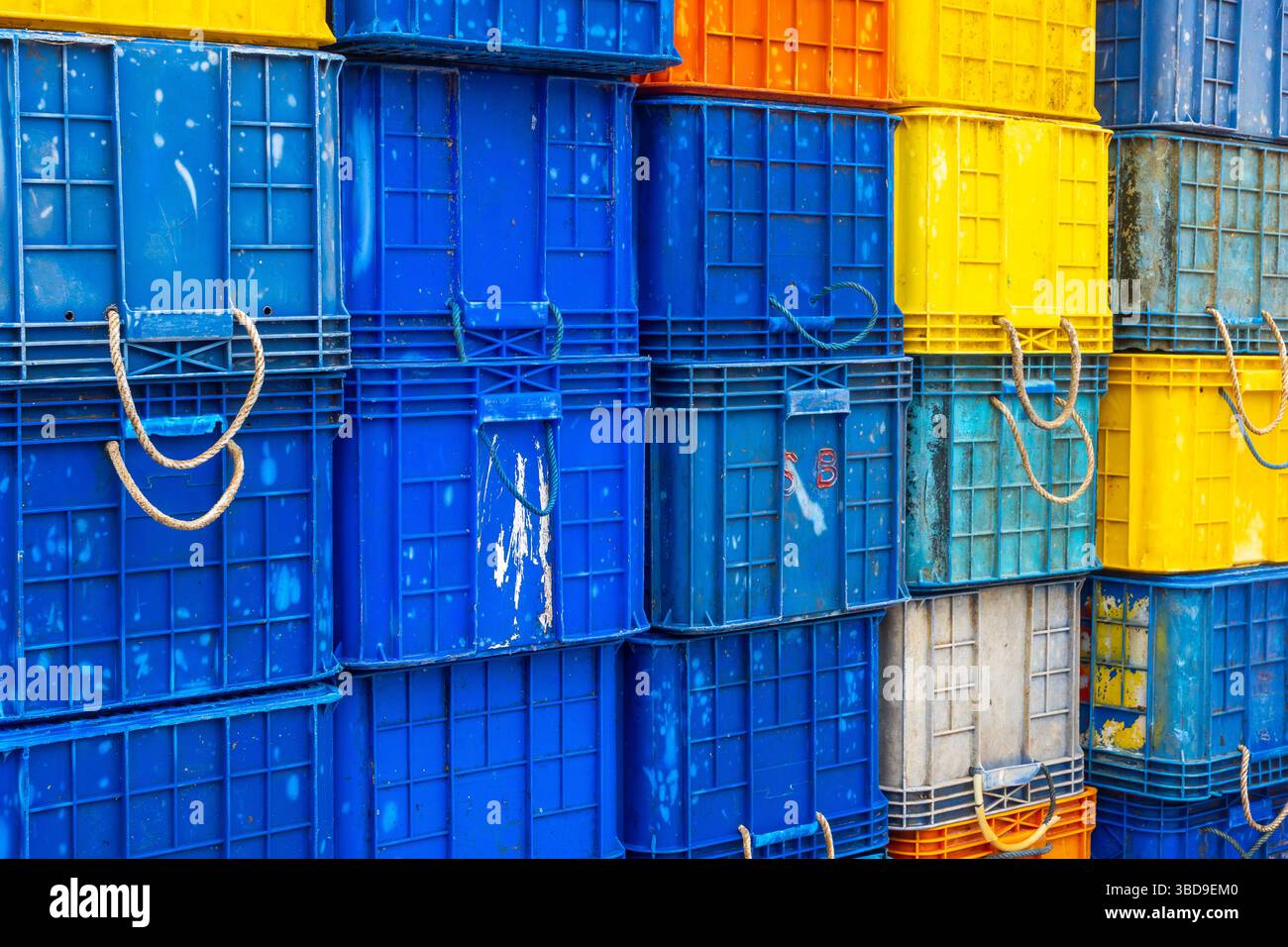 Stack of blue and yellow crates. The crates are stacked on top of each ...