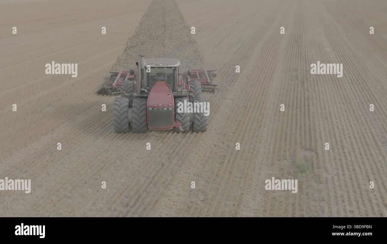 Big red Tractor Pulling Disc Harrow Through Field in Preparation soil ...