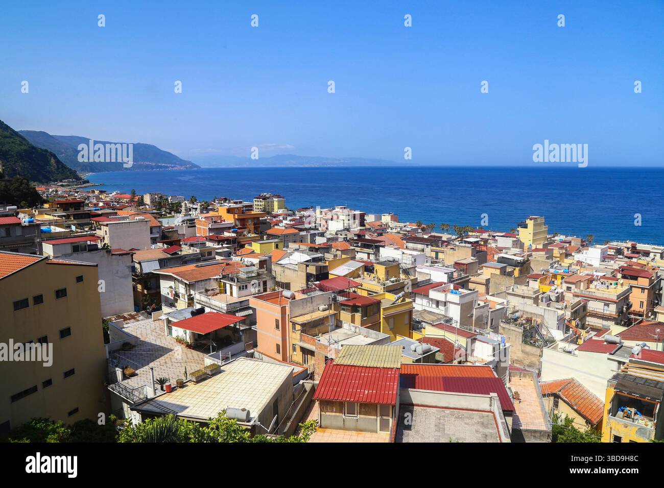 A colorful coastal town with densely packed buildings sprawls along the ...