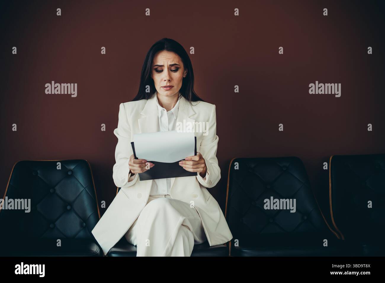 Beautiful female professional reviews documents while seated in an ...