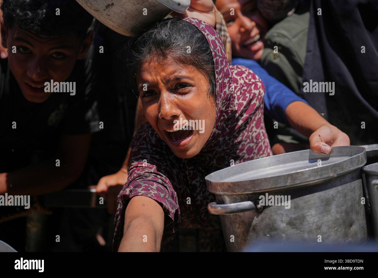 Palestinians struggle to receive cooked food distributed at a community ...