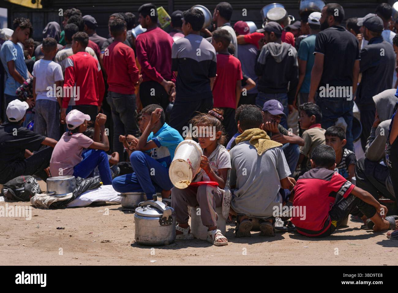 Palestinians wait to receive cooked food distributed at a community ...